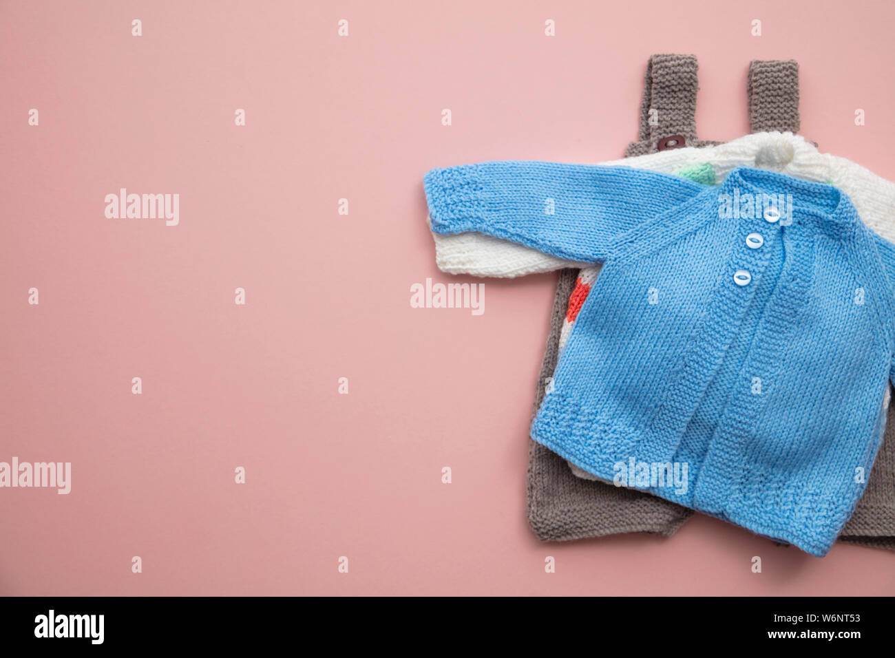 Cute knitted baby clothes layout on a pastel pink background Stock ...