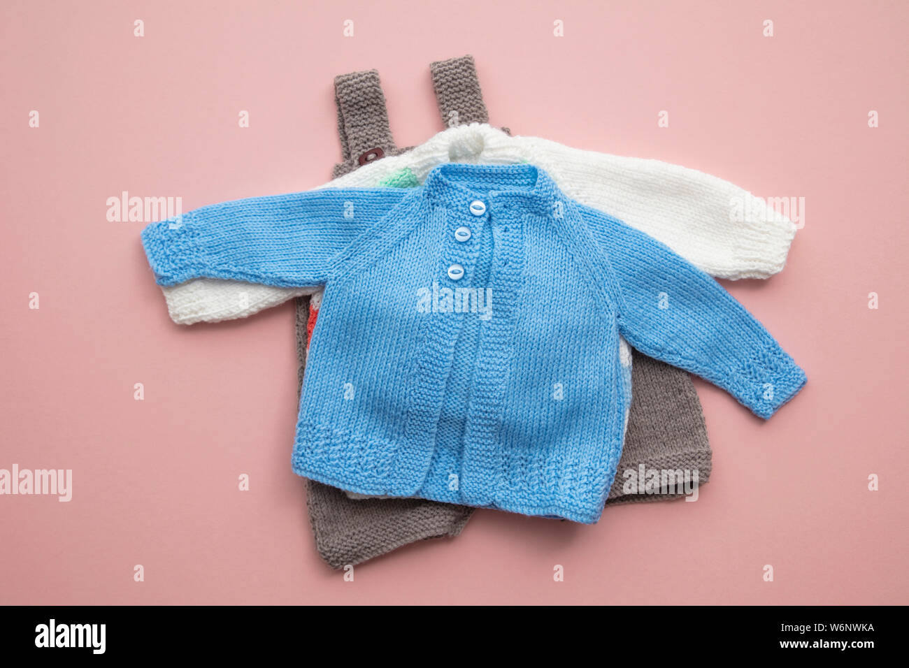 Cute knitted baby clothes layout on a pastel pink background Stock ...