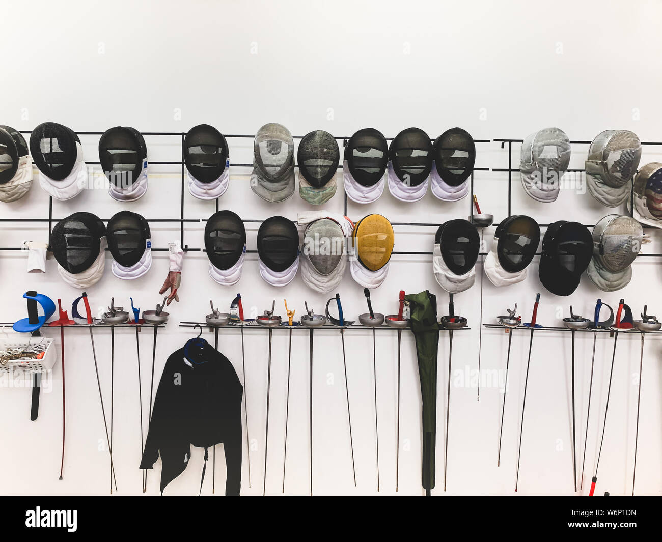 Group of fencing masks and sword hanging on the wall Stock Photo - Alamy