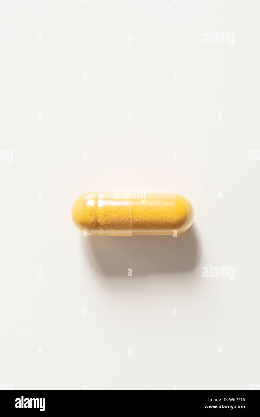 Single turmeric capsule isolated on a white background. Please credit ...