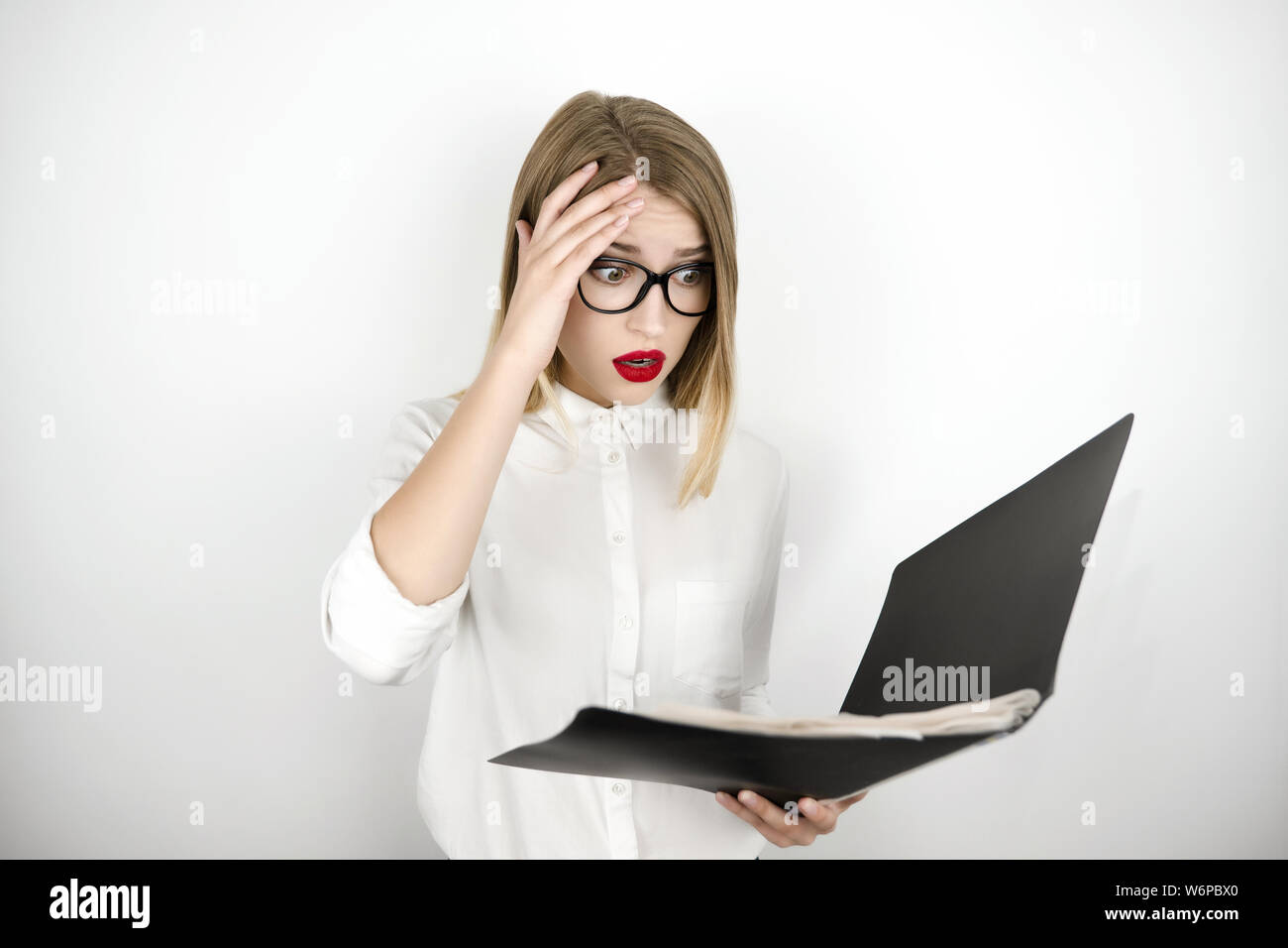 young beautiful business woman in eyeglasses looks confused holding ...