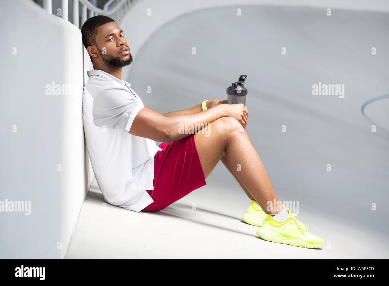 Tired handsome young male runner sitting on the ground Stock Photo - Alamy