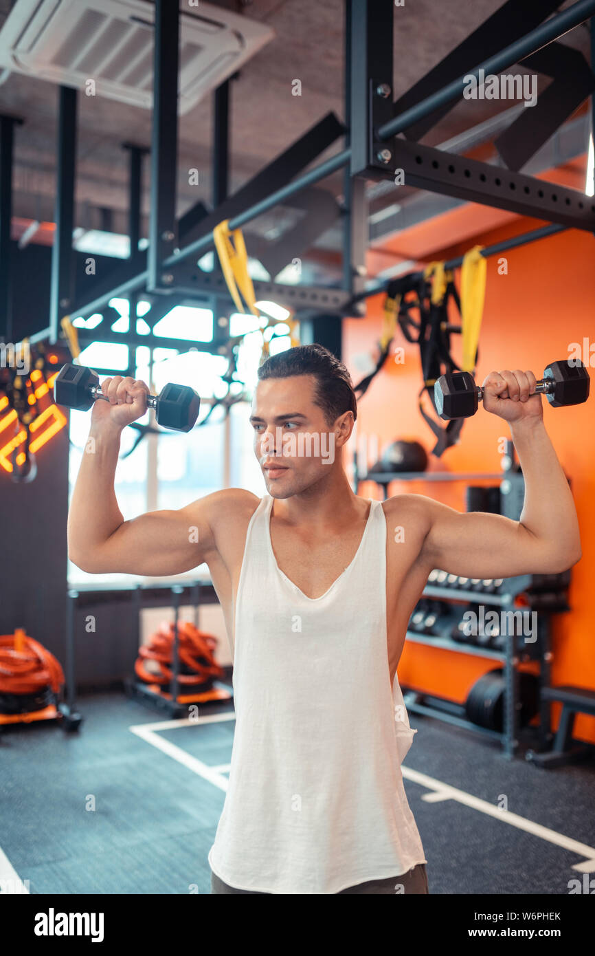 Positive fit young man standing with dumbbells Stock Photo - Alamy
