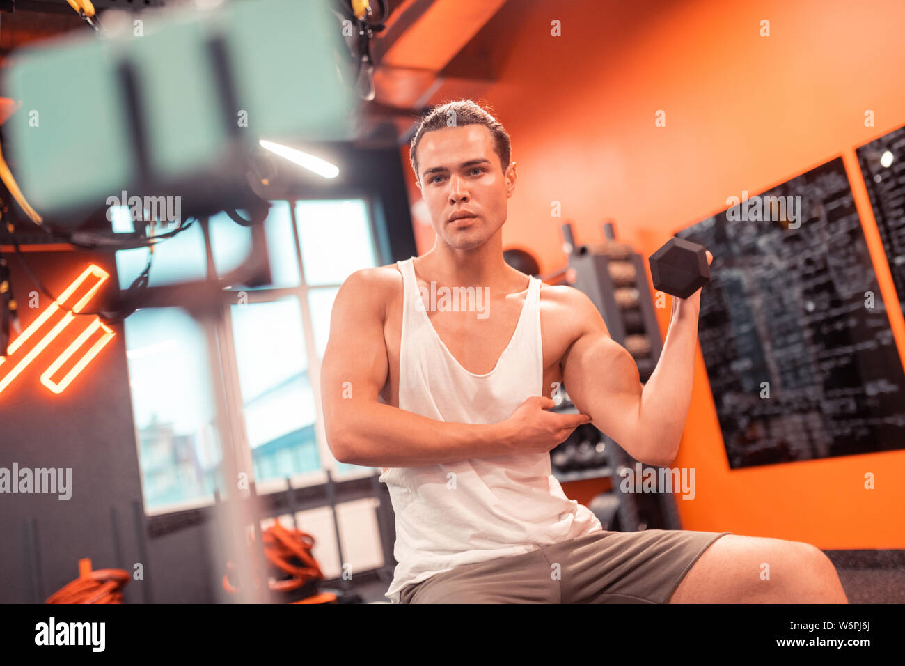 Serious good looking man showing his muscles on camera Stock Photo - Alamy