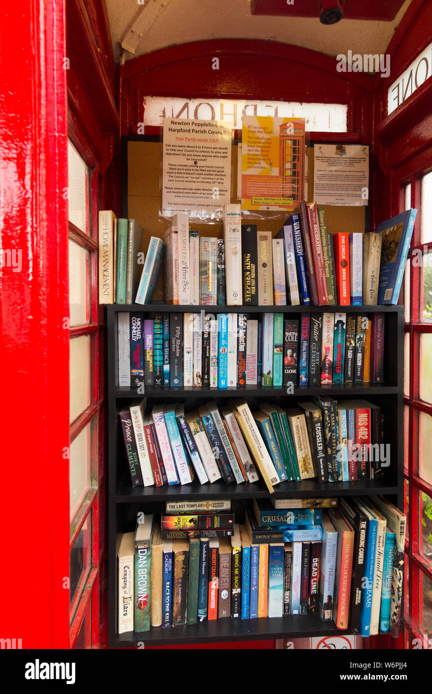 Books on shelves forming a little local library in an old red phone box ...