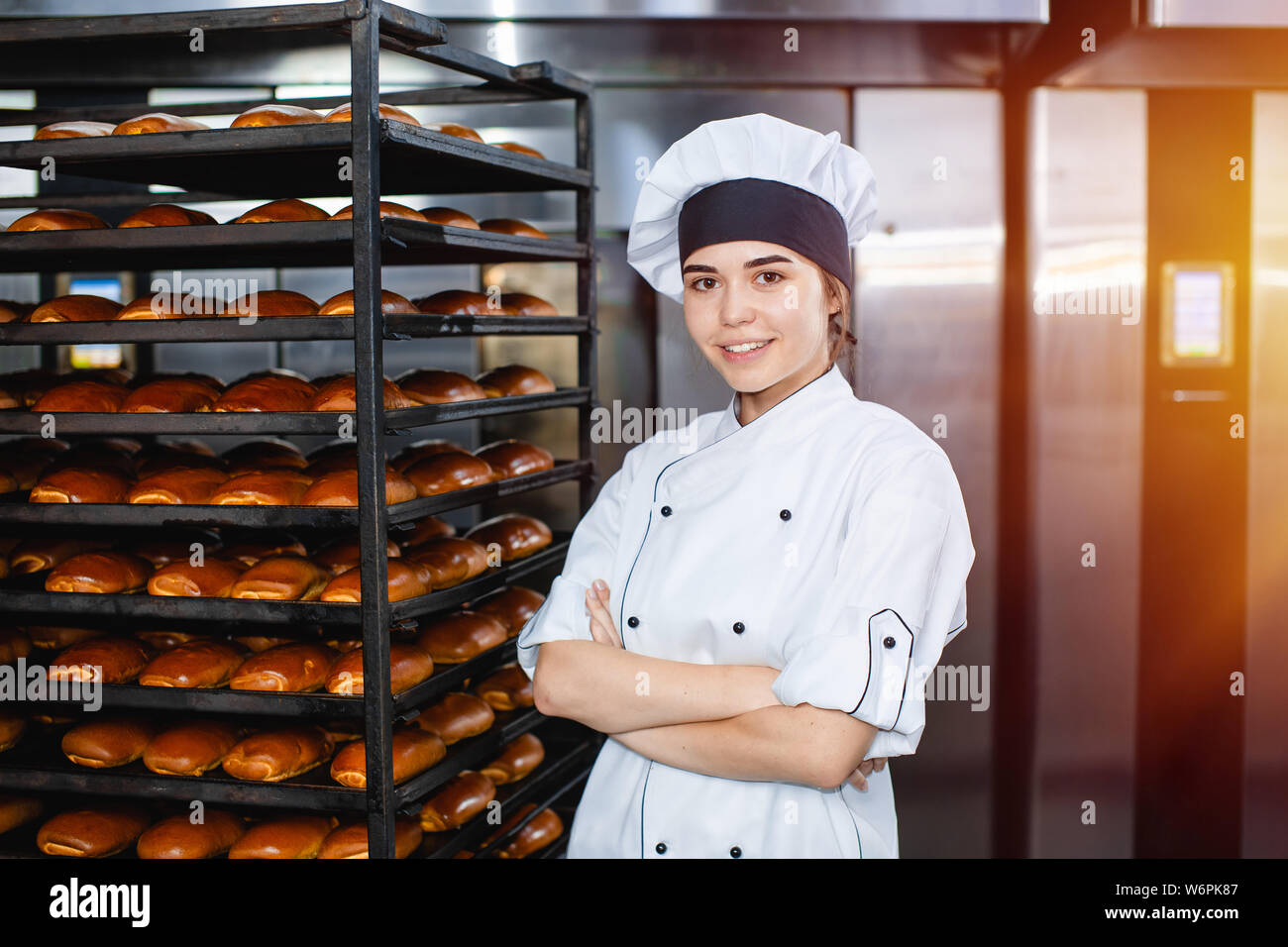 Portrait of a young baker girl on the background of an industrial oven ...