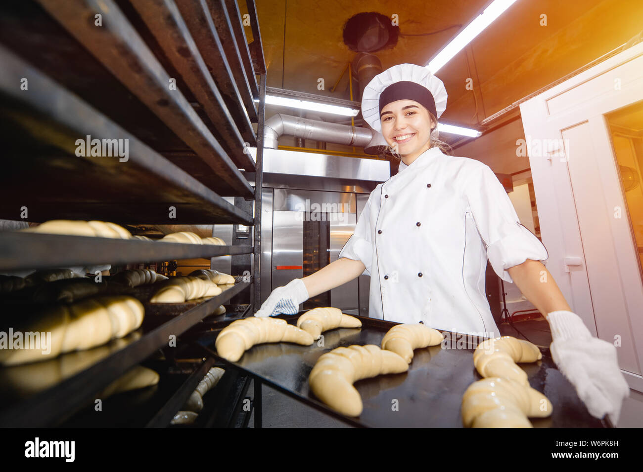 Baker girl with a baking sheet with raw dough in hands on the ...