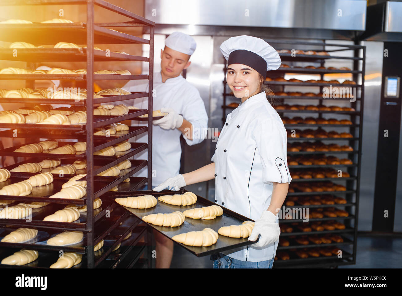 Baker girl with a baking sheet with raw dough in hands on the ...