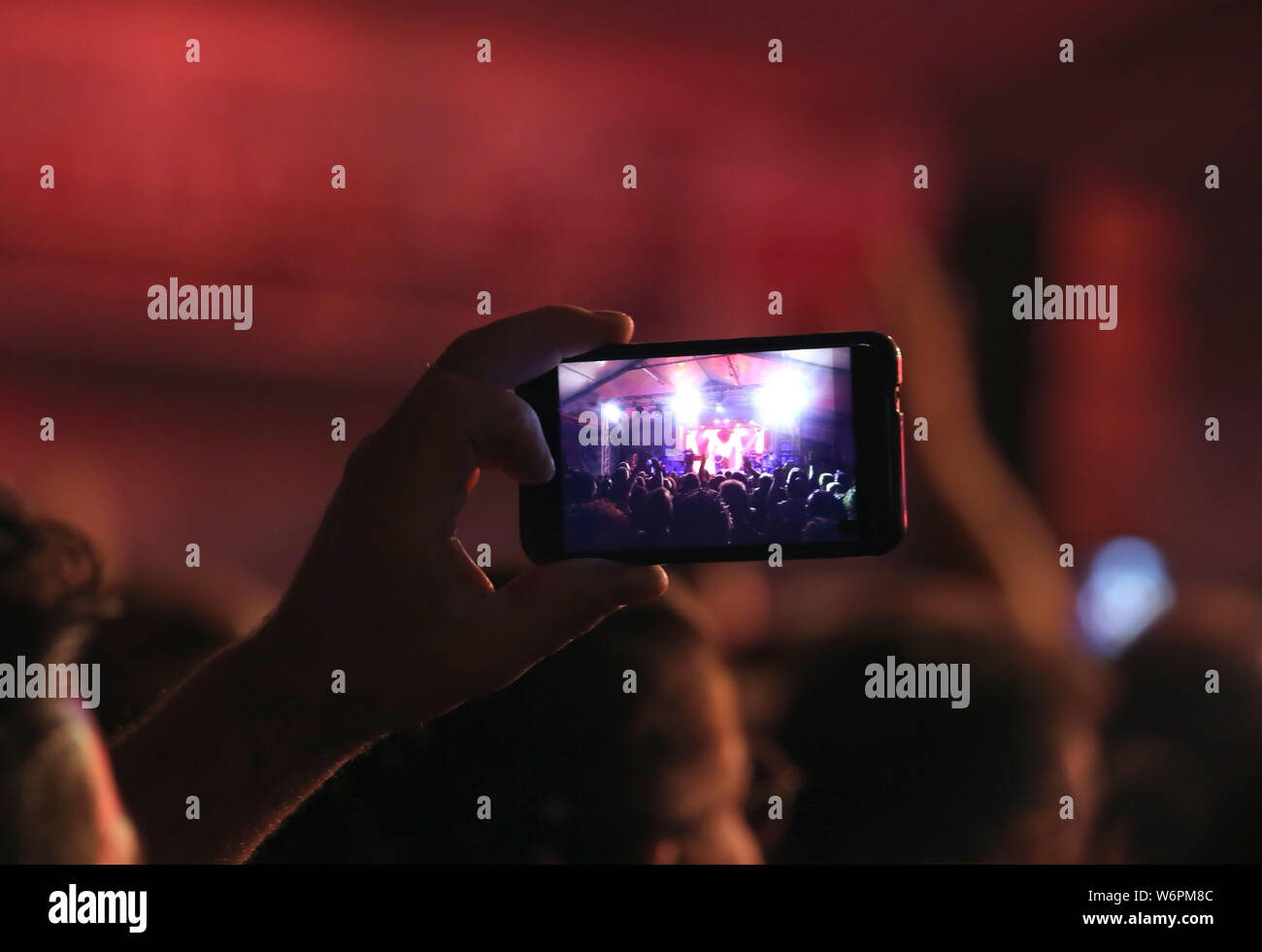 spectator of a concert photographs with his mobile phone the singer ...
