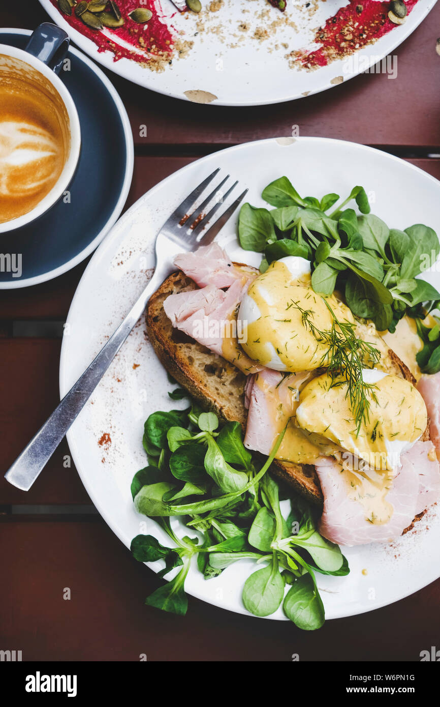 Trendy breakfast set. Flat-lay of poached Eggs Benedict on sourdough ...