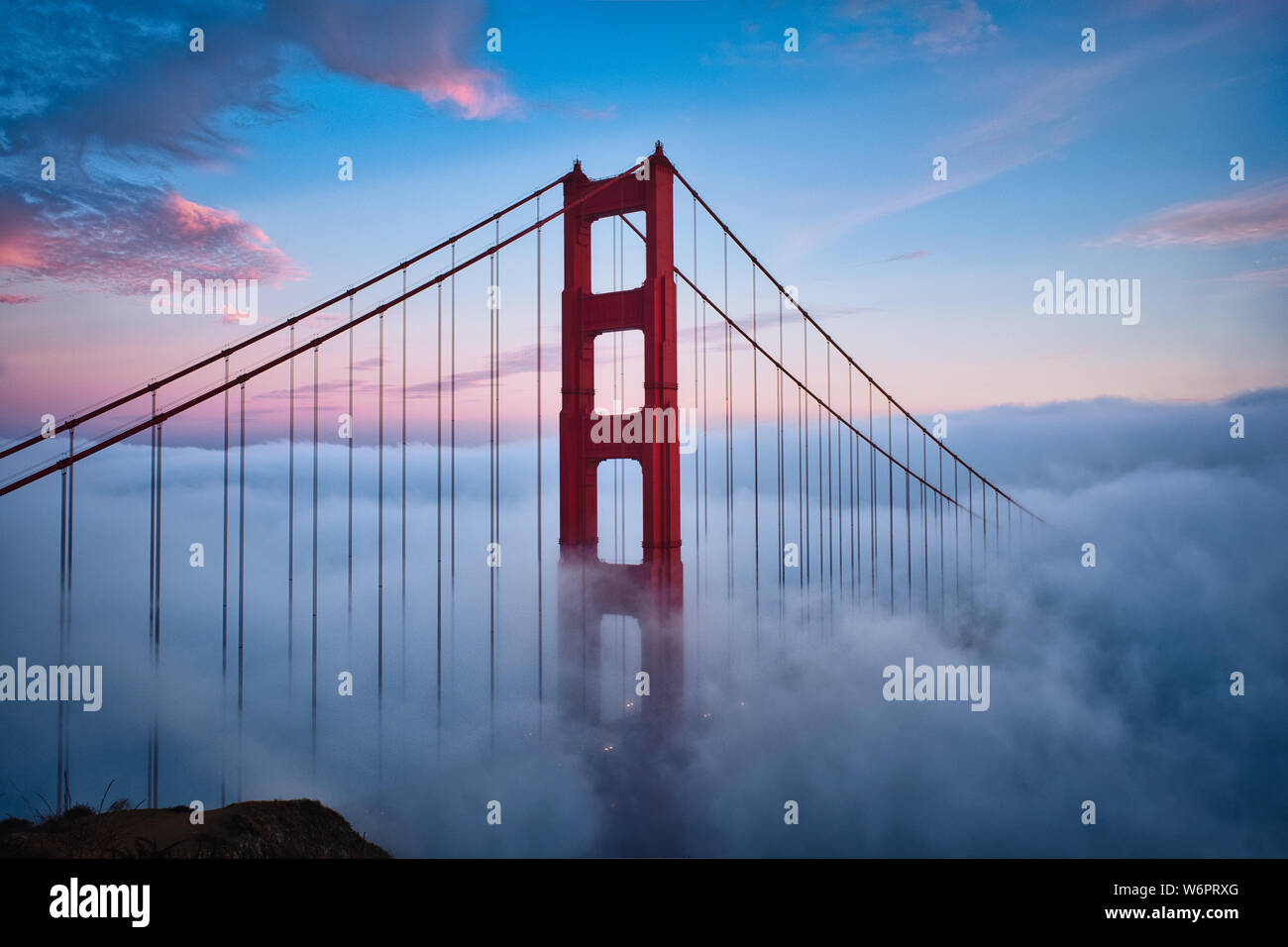 Photo of the Golden Gate Bridge at the sunset time covered with clouds ...