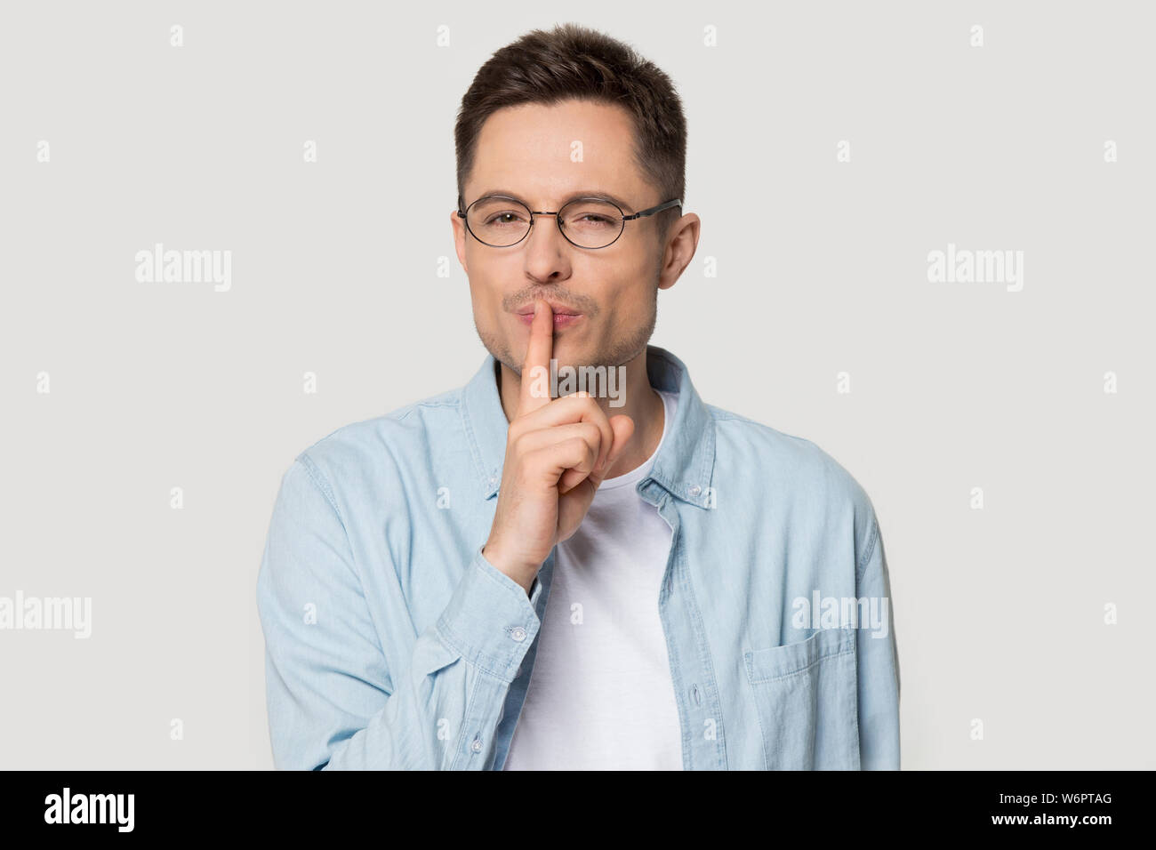 Headshot portrait man makes hush gesture pose over grey background ...