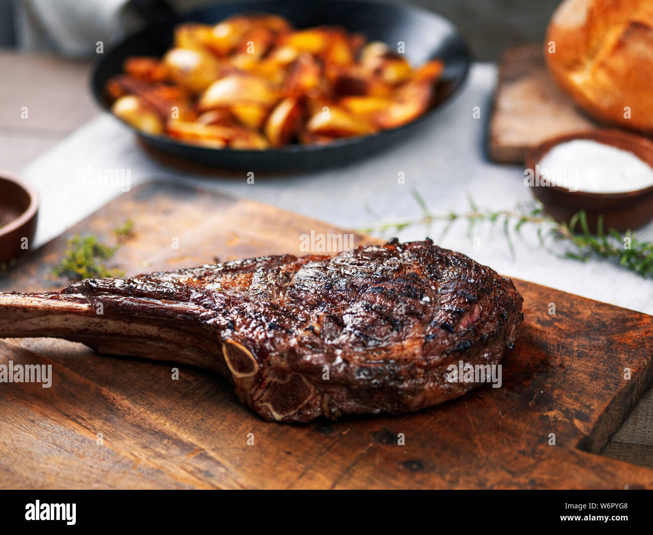 Grilled angus beef tomahawk steak on a cutting board with roasted ...