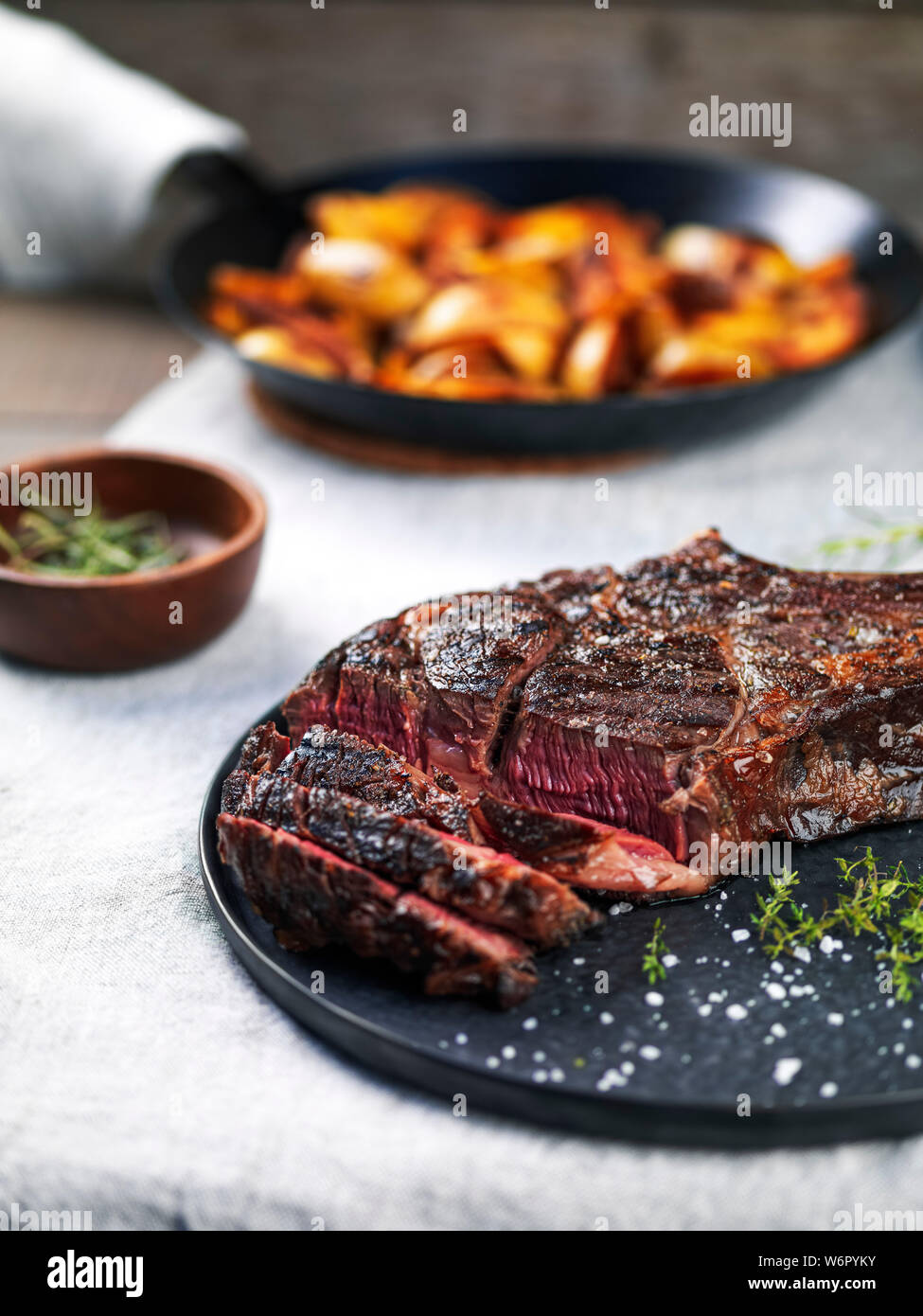 Sliced medium rare grilled angus beef tomahawk steak on a dark plate ...