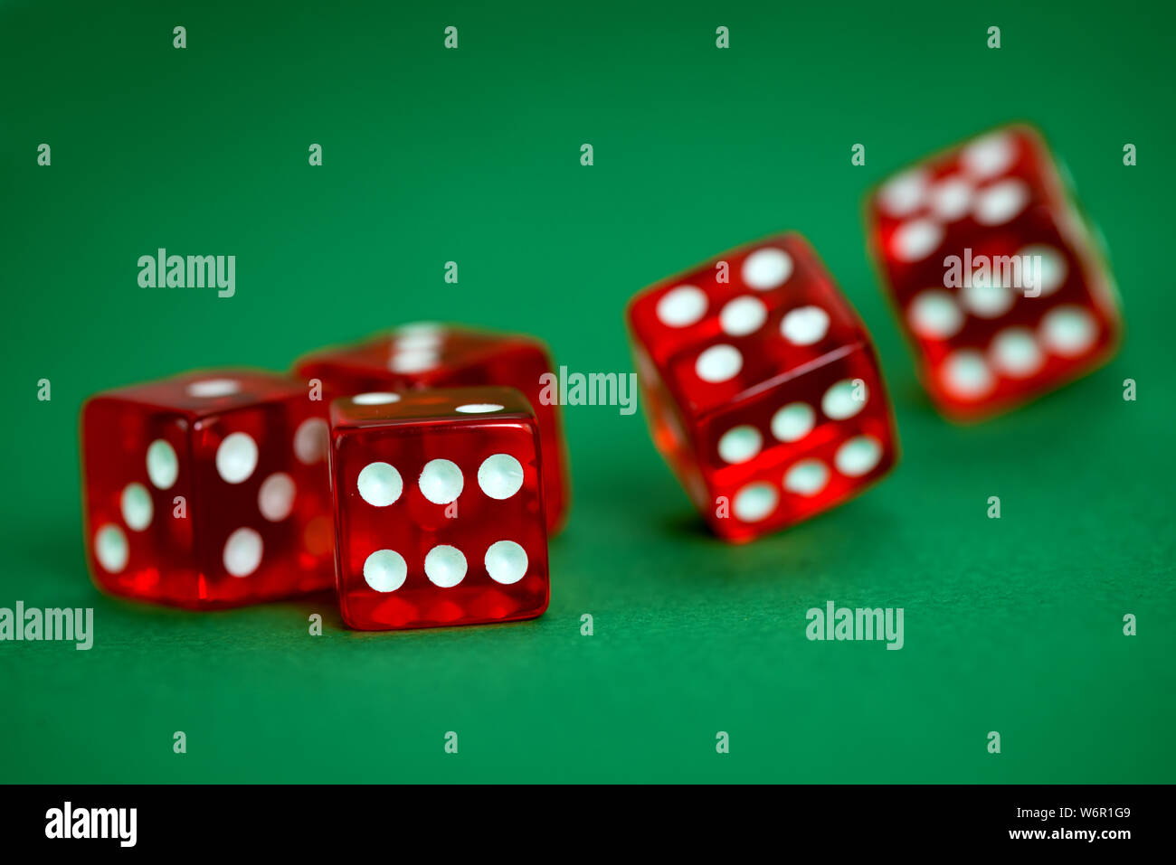 five rolling red dices on green background Stock Photo - Alamy