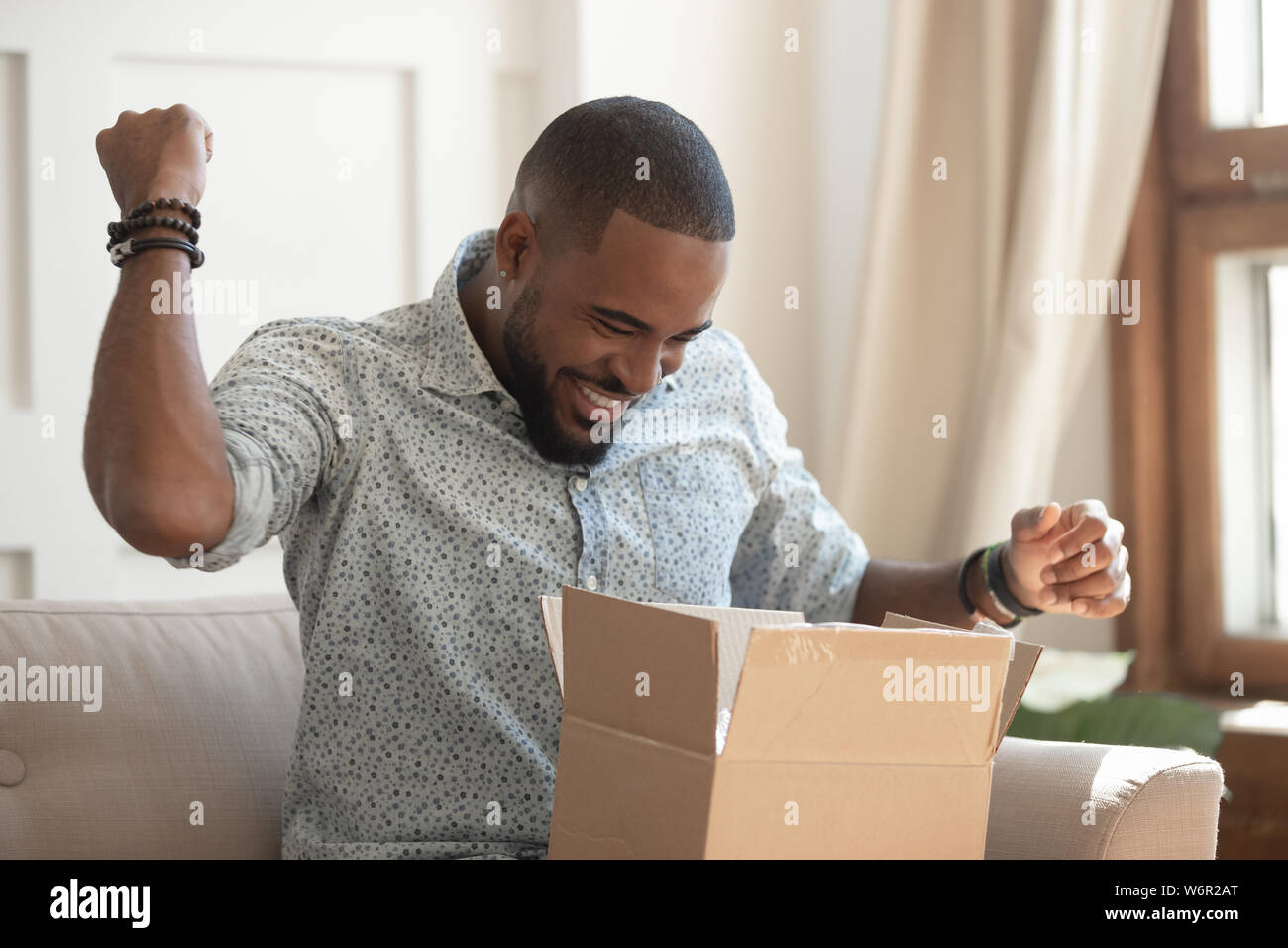 Excited african man customer receive open parcel box at home Stock ...