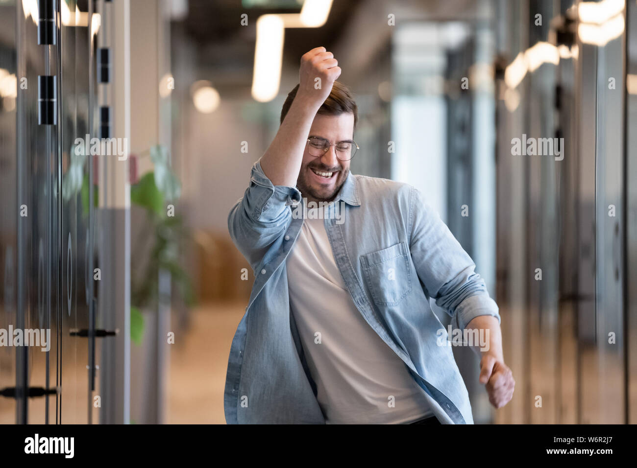 Ecstatic male winner dancing in office hallway laughing celebrating ...