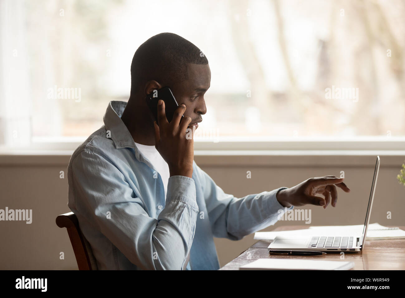 African guy looking at computer screen talk on phone Stock Photo - Alamy