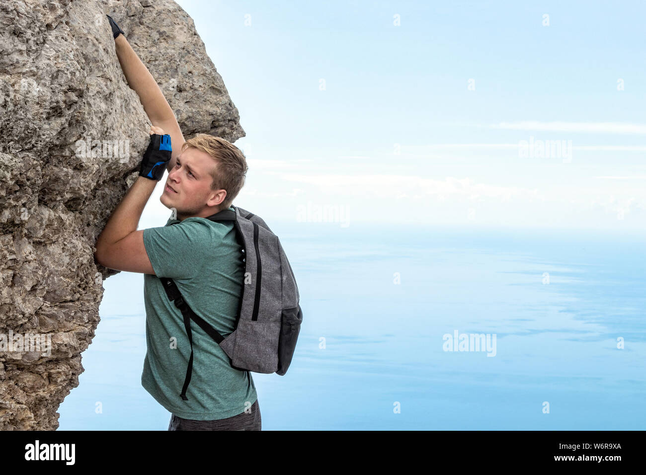 Young man climbing, hanging on edge Stock Photo - Alamy