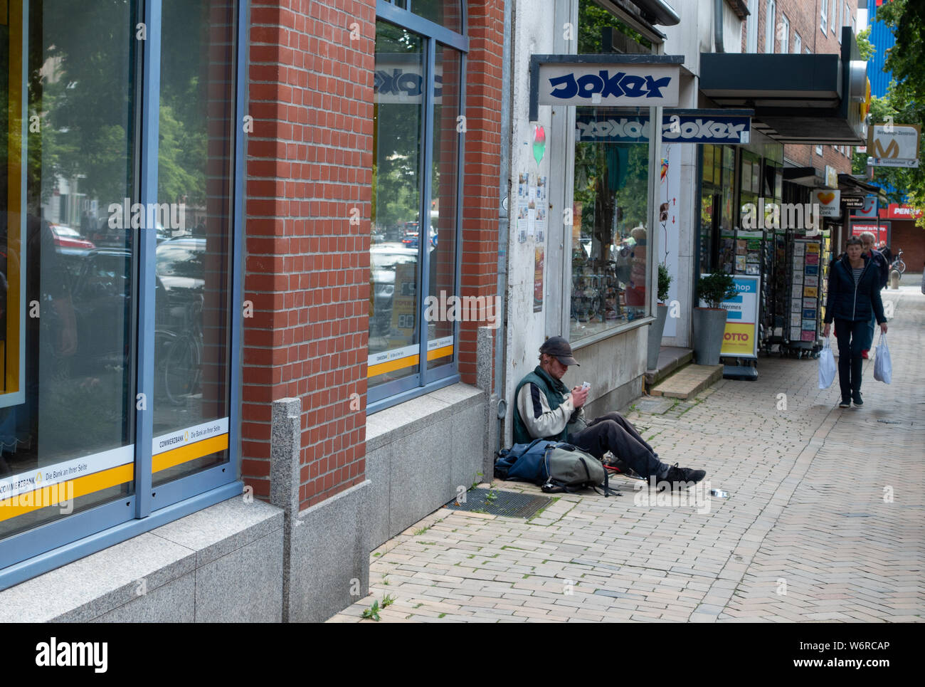 Beggar sitting at side of road with a mobile phone Stock Photo - Alamy