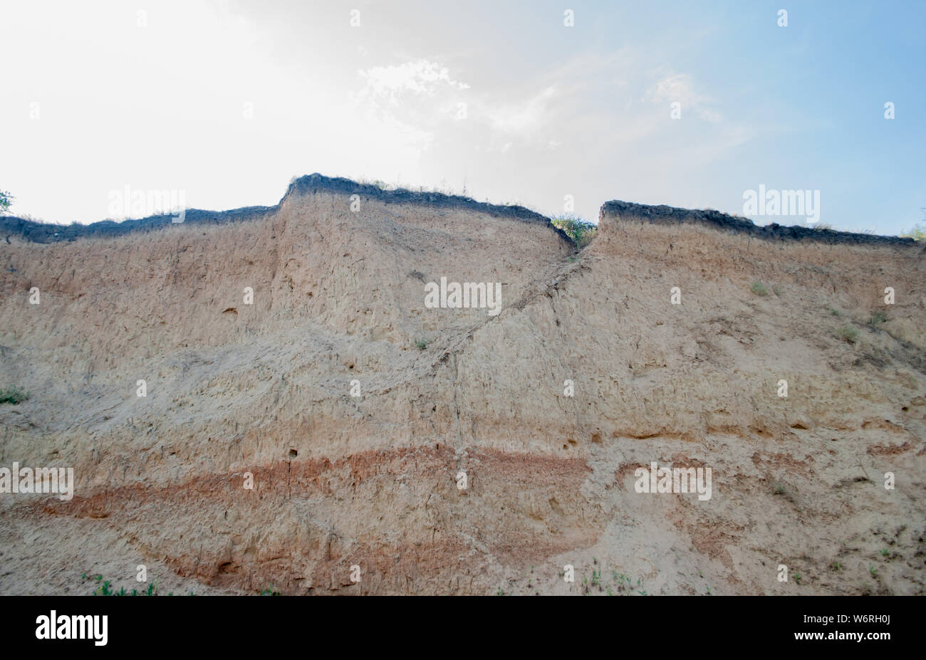A cliff where soil layers are visible in a section, and above it sky ...