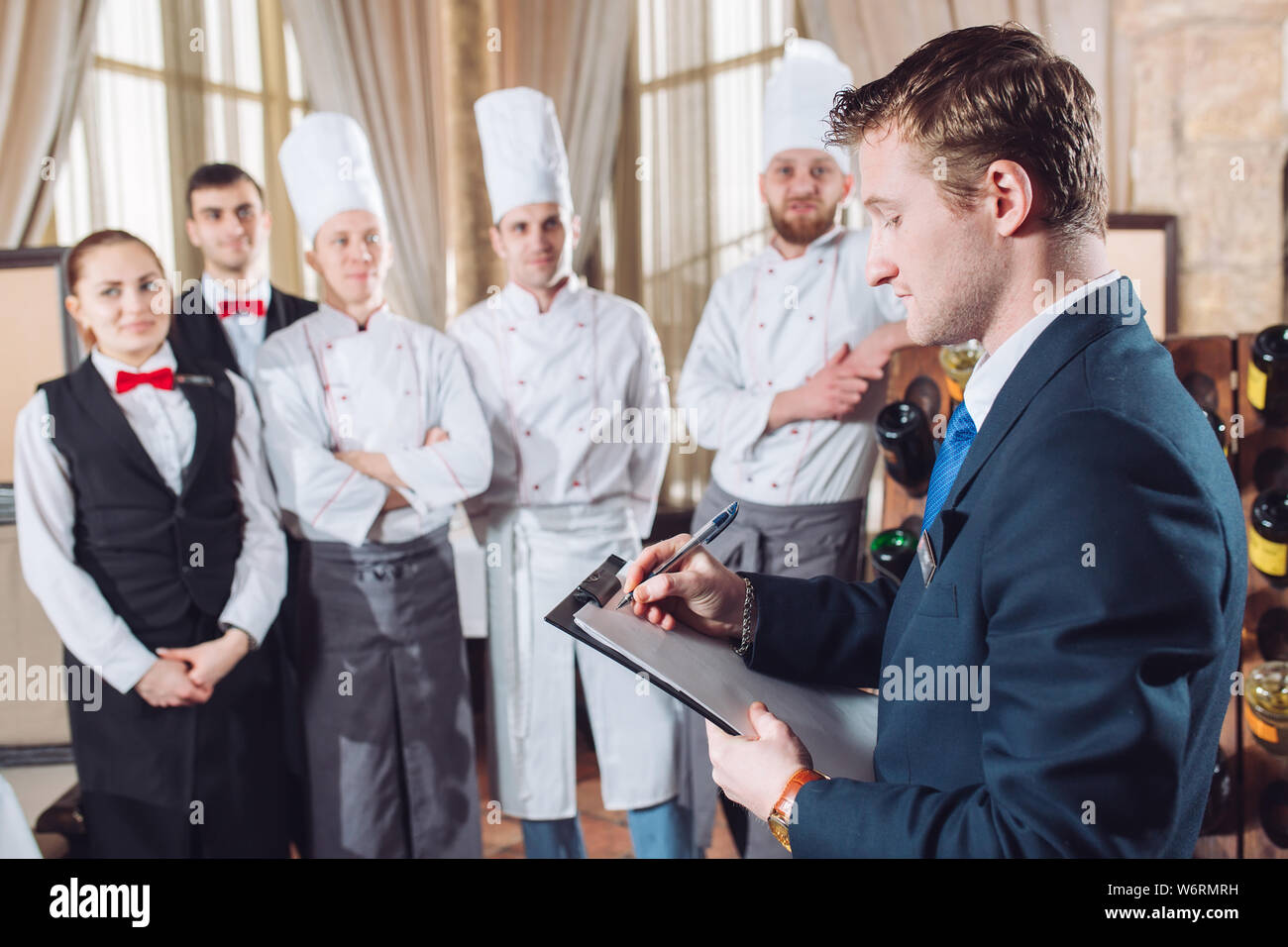 restaurant manager and his staff in kitchen. interacting to head chef ...