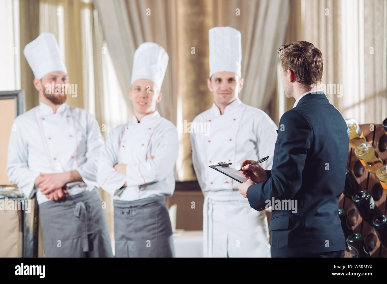 restaurant manager and his staff in kitchen. interacting to head chef ...