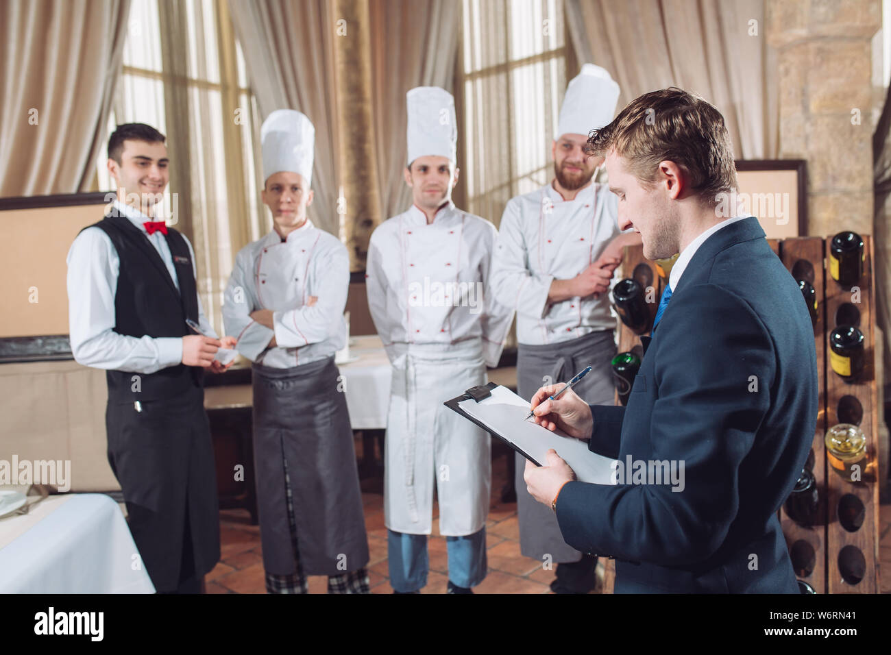 restaurant manager and his staff in kitchen. interacting to head chef ...