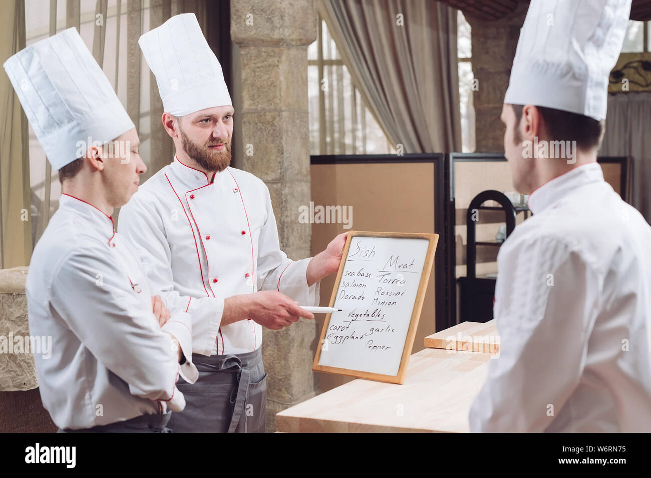 Head Chef and his staff in kitchen. interacting to in commercial ...