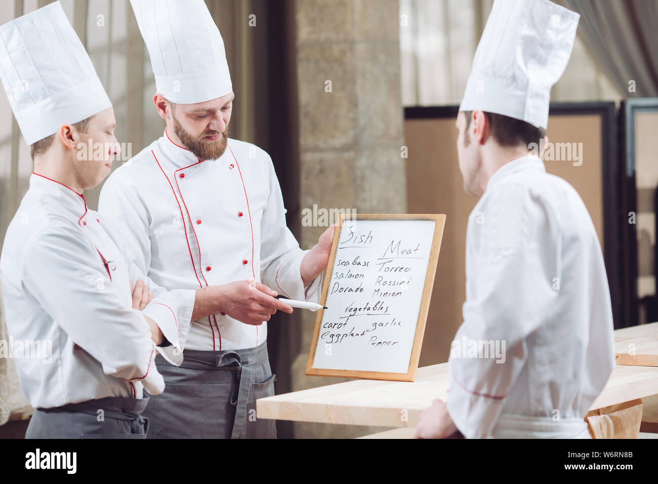 Head Chef and his staff in kitchen. interacting to in commercial ...