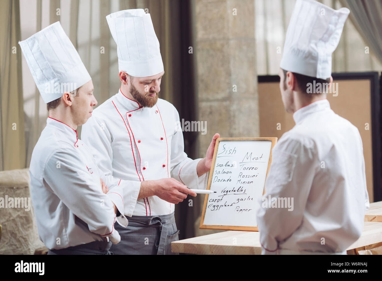 Head Chef and his staff in kitchen. interacting to in commercial ...