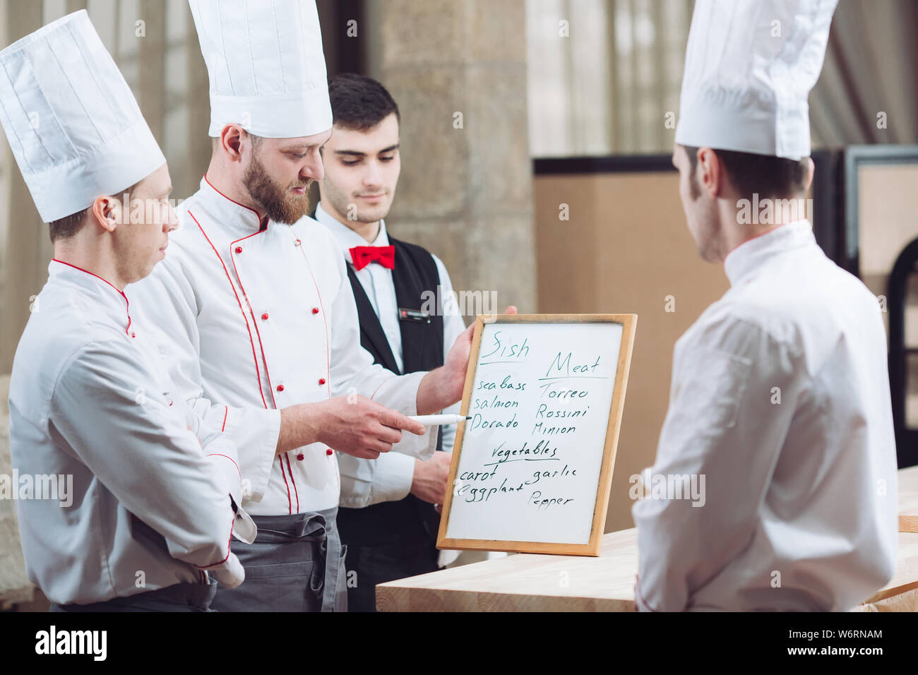 Head Chef and his staff in kitchen. interacting to in commercial ...