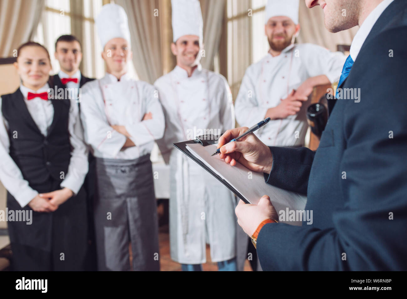 restaurant manager and his staff in kitchen. interacting to head chef ...