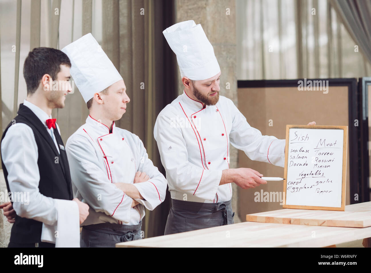 Head Chef and his staff in kitchen. interacting to in commercial ...