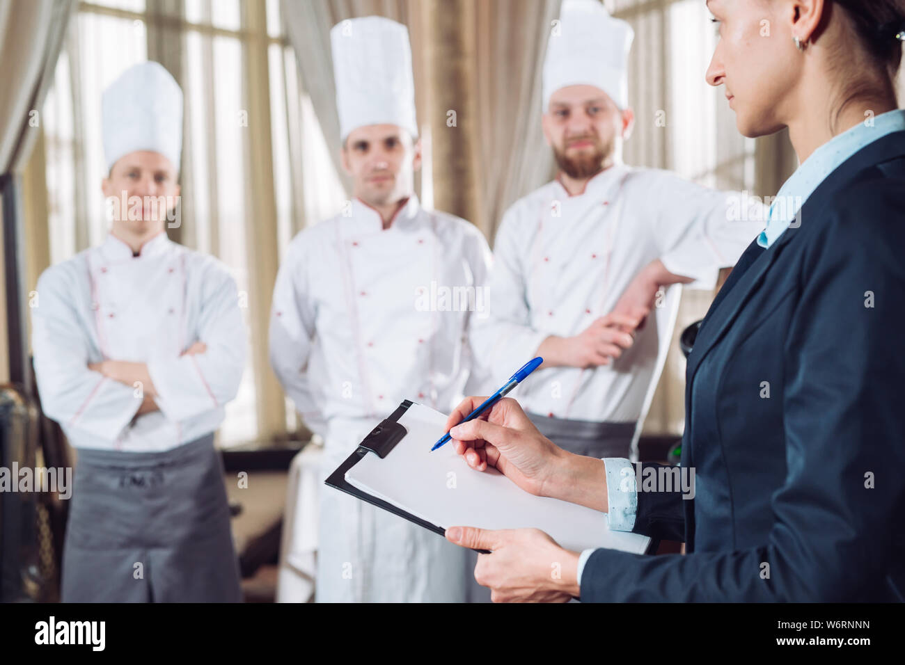 restaurant manager and his staff in kitchen. interacting to head chef ...