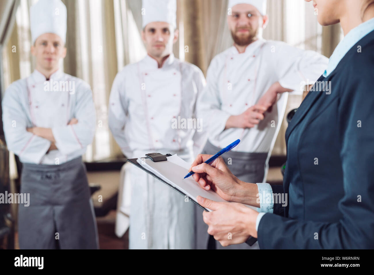 restaurant manager and his staff in kitchen. interacting to head chef ...