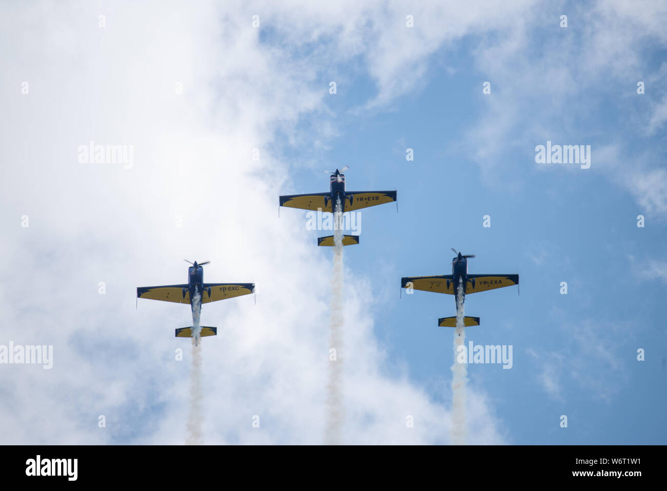 Three airplanes in the sky within clouds performing acrobatics during ...