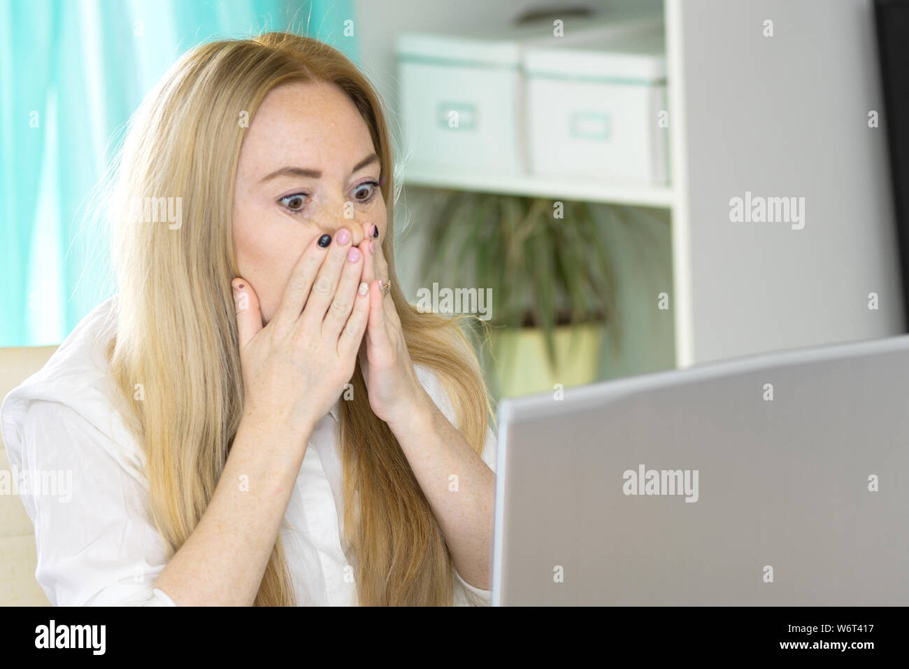 Portrait young shocked business woman sitting in front of laptop ...