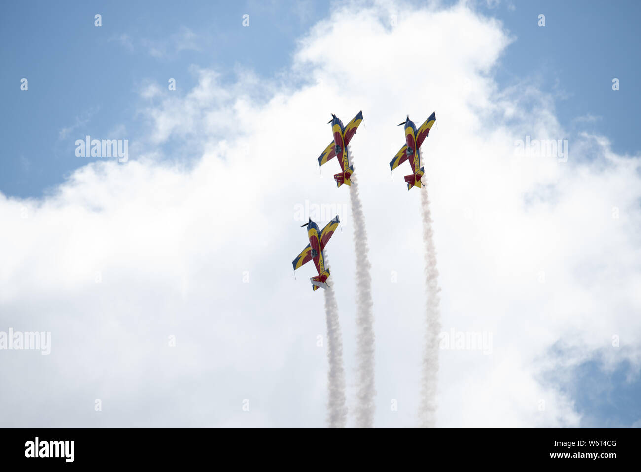 Three airplanes in the sky within clouds performing acrobatics during ...