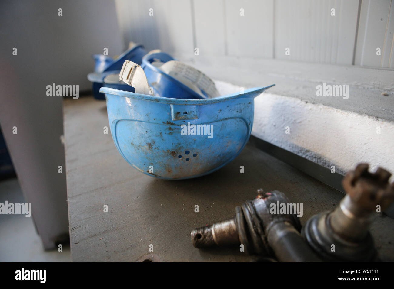 Dirty blue worker helmets on top of an old, rusty and dirty workbench ...