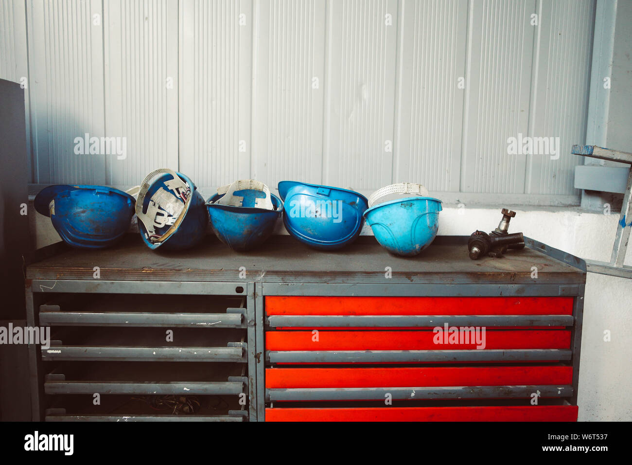 Dirty blue worker helmets on top of an old, rusty and dirty workbench ...