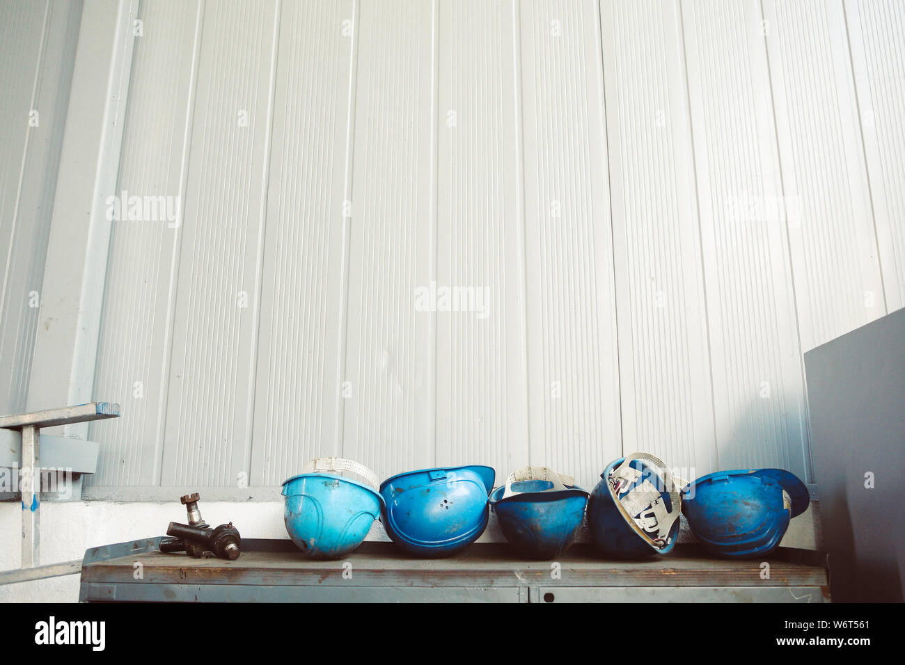 Dirty blue worker helmets on top of an old, rusty and dirty workbench ...