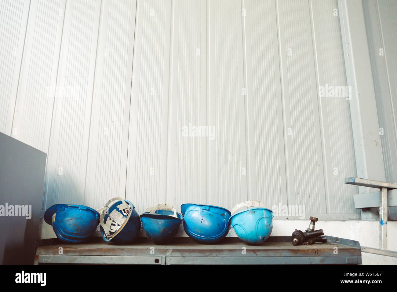 Dirty blue worker helmets on top of an old, rusty and dirty workbench ...