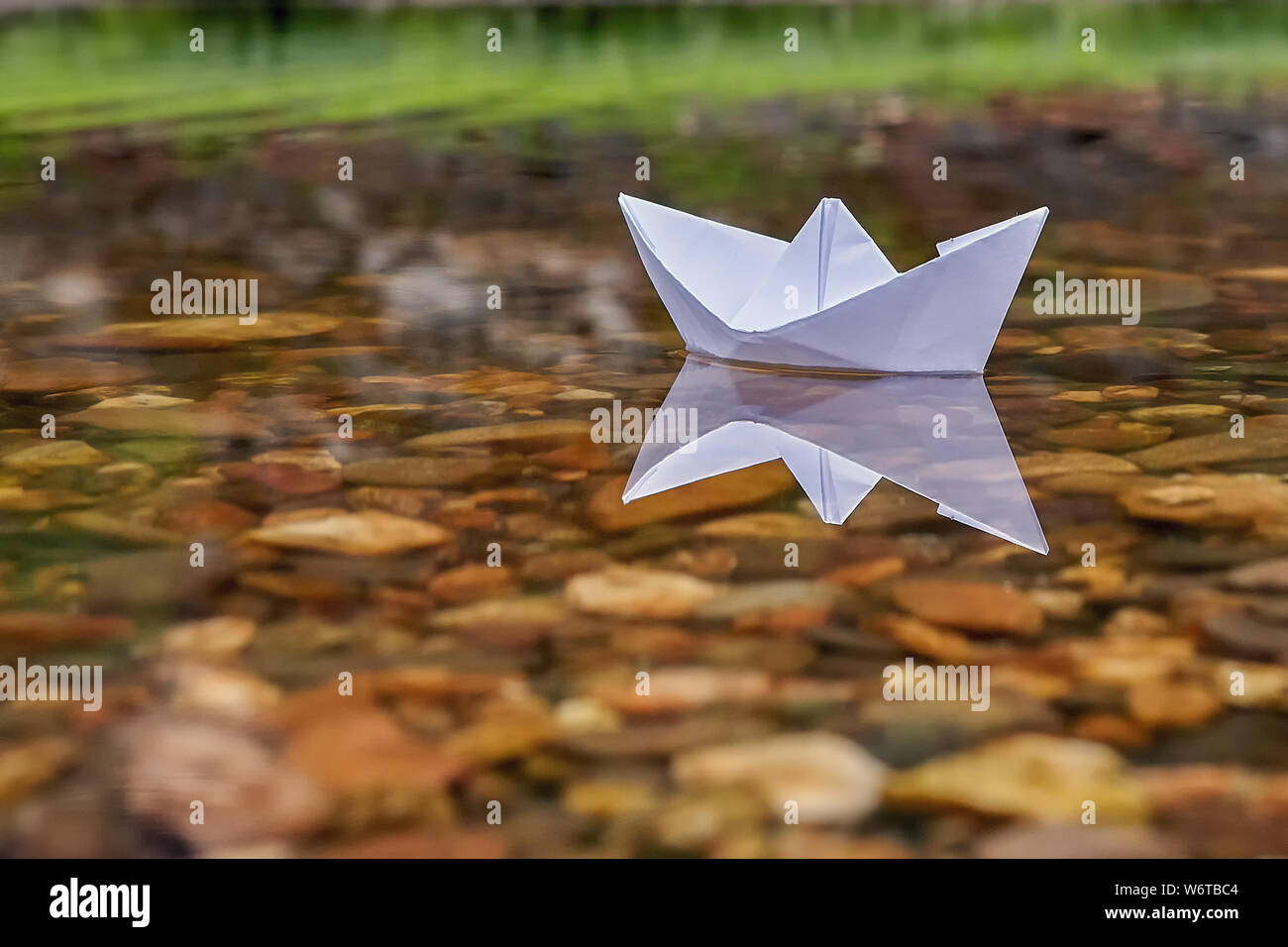 White paper boat on the surface of quiet river in taiga forest as a ...