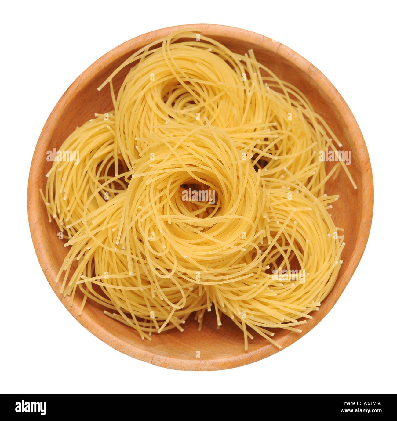 bunches of nested noodle pasta in wooden bowl isolated on white ...