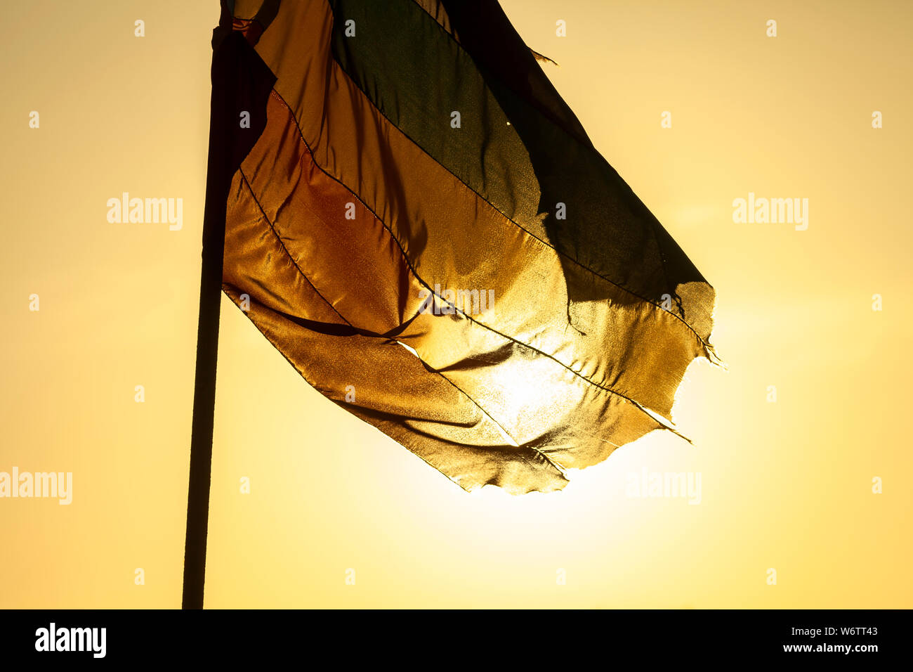 Backlit frayed LGBT flag with washed out colours from the morning sun ...