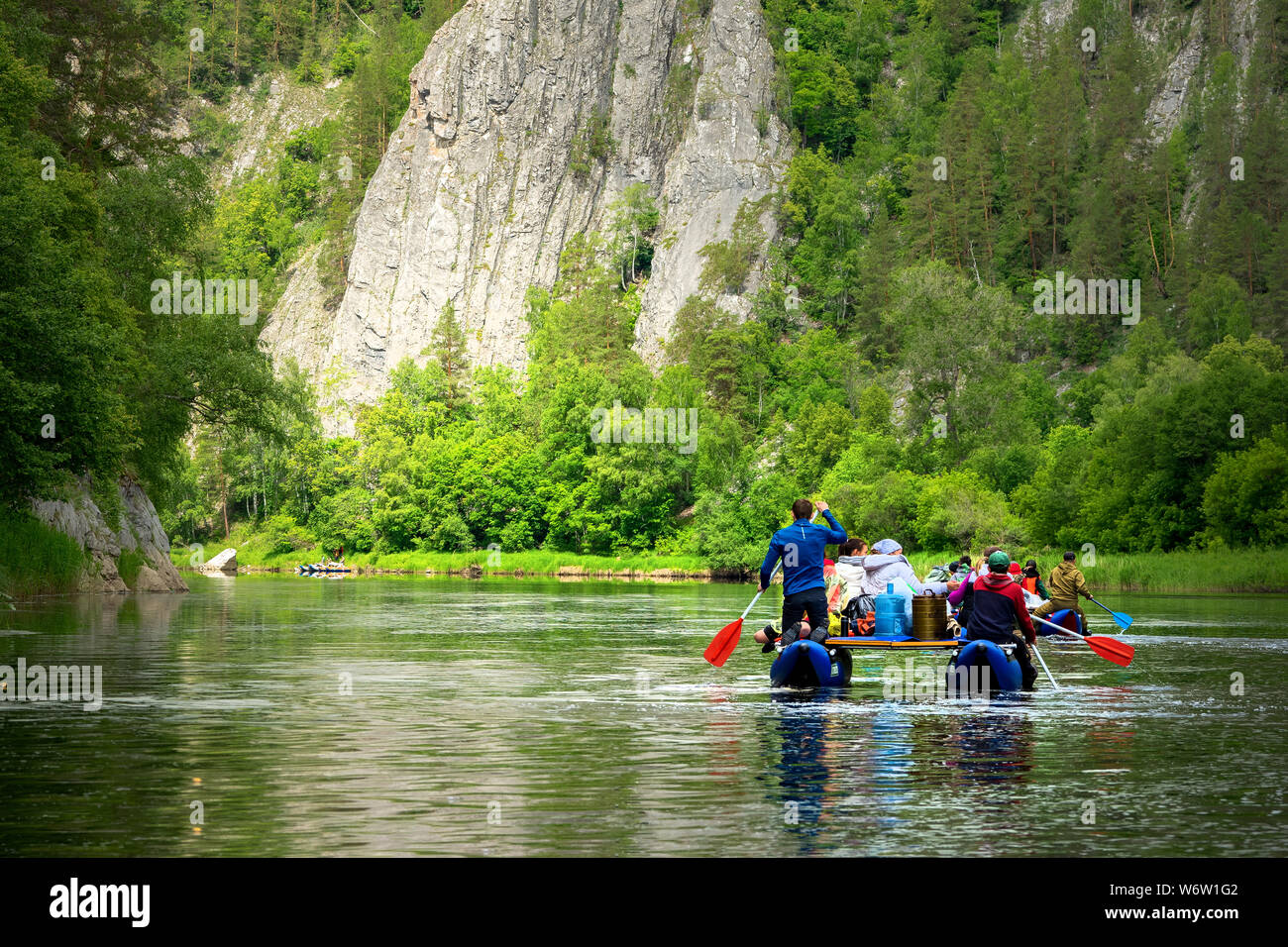 A group of friends in an inflatable raft moving down a river. Mountain ...