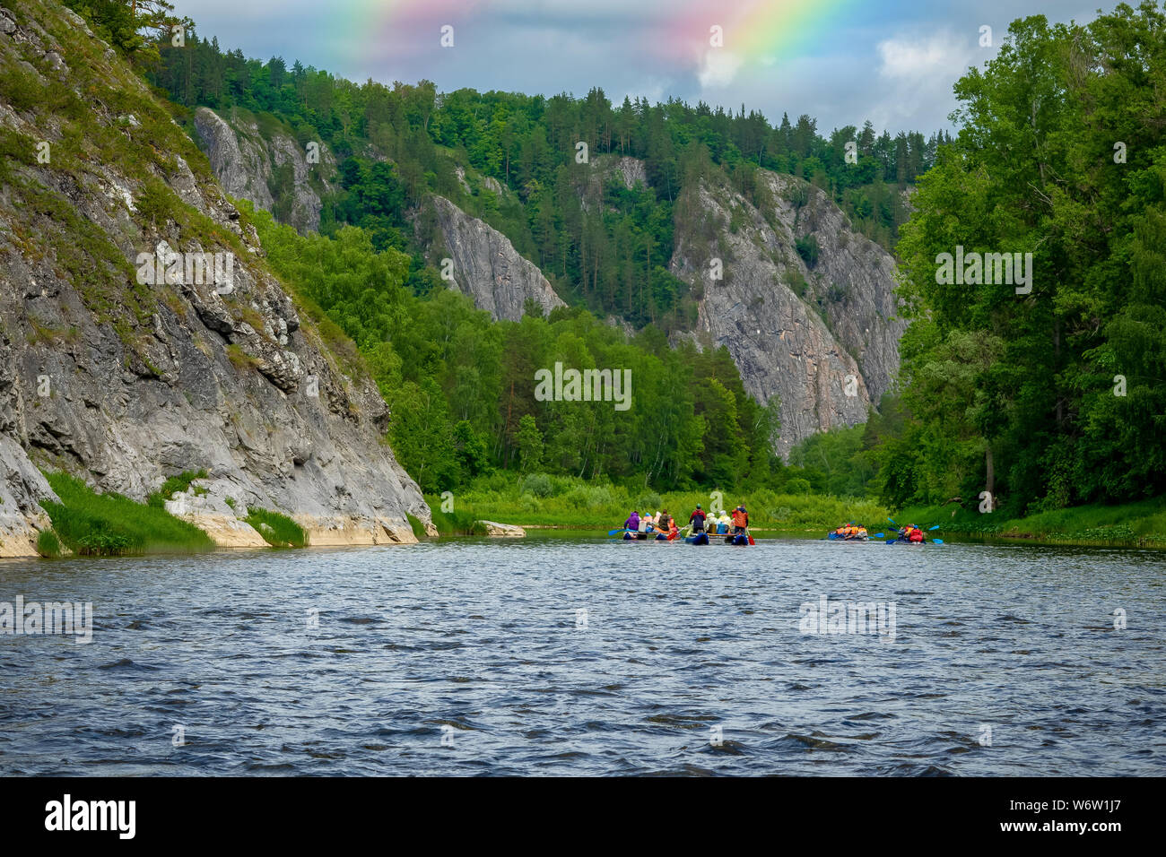 A group of friends in an inflatable raft moving down a river. Mountain ...
