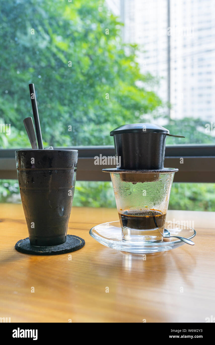 Vietnamese iced fin coffee next to window with cityscape background ...