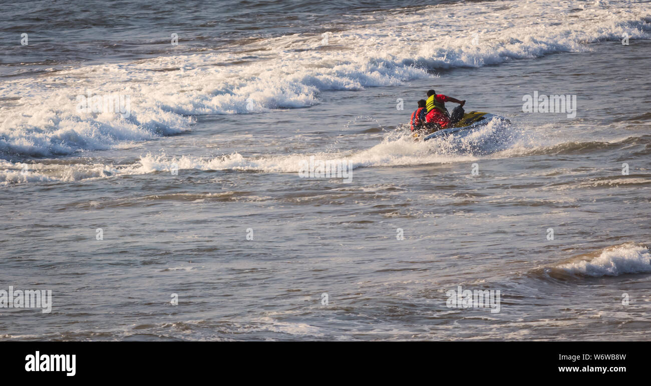 Young couple riding a jet ski / wave runner in Goa sea, wearing safety ...